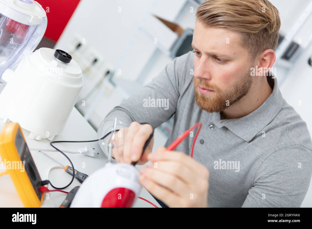 man sitting by desk repairing a blender Stock Photo - Alamy
