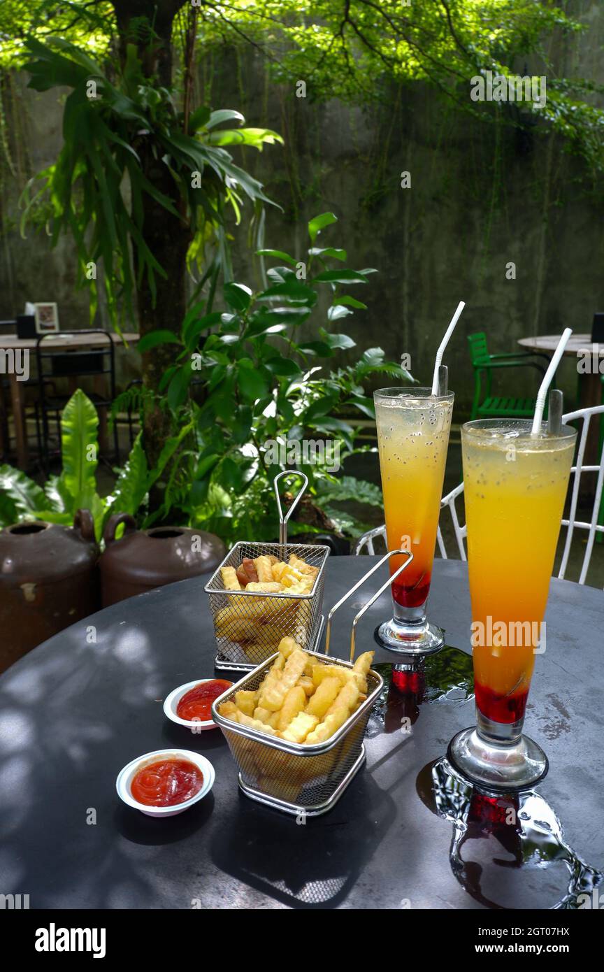 Vertical shot of french fries in baskets on the table with iced drinks ...