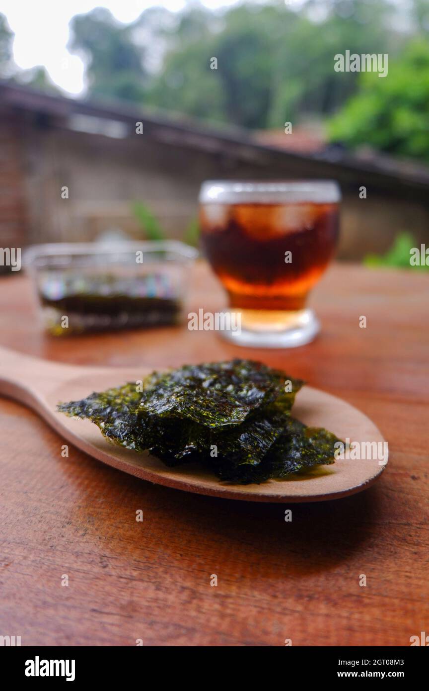 Vertical shot of chopped seaweed on a wooden scoop on the table with a ...