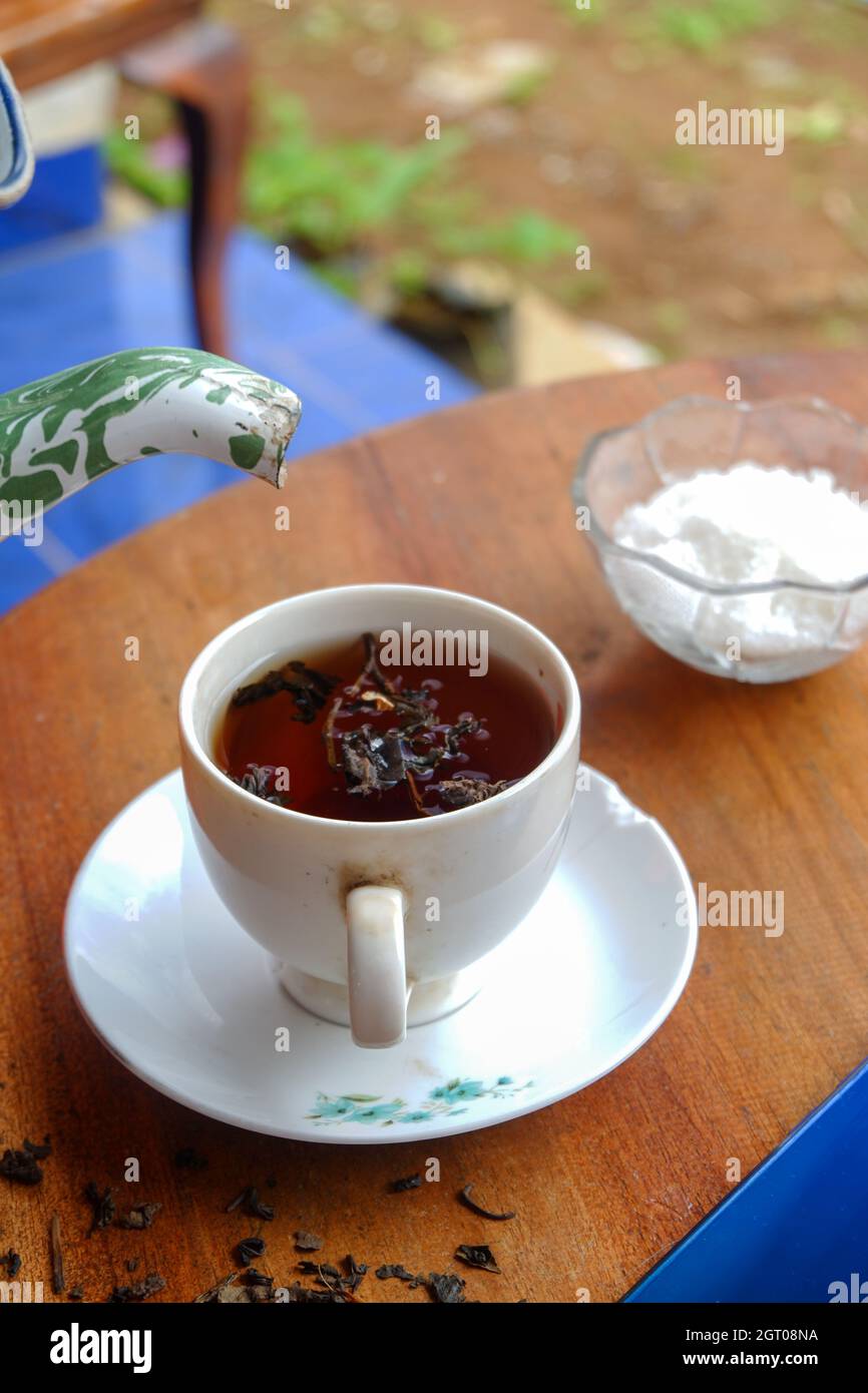 Vertical shot of a cup of hot tea on the table with a blurry background ...