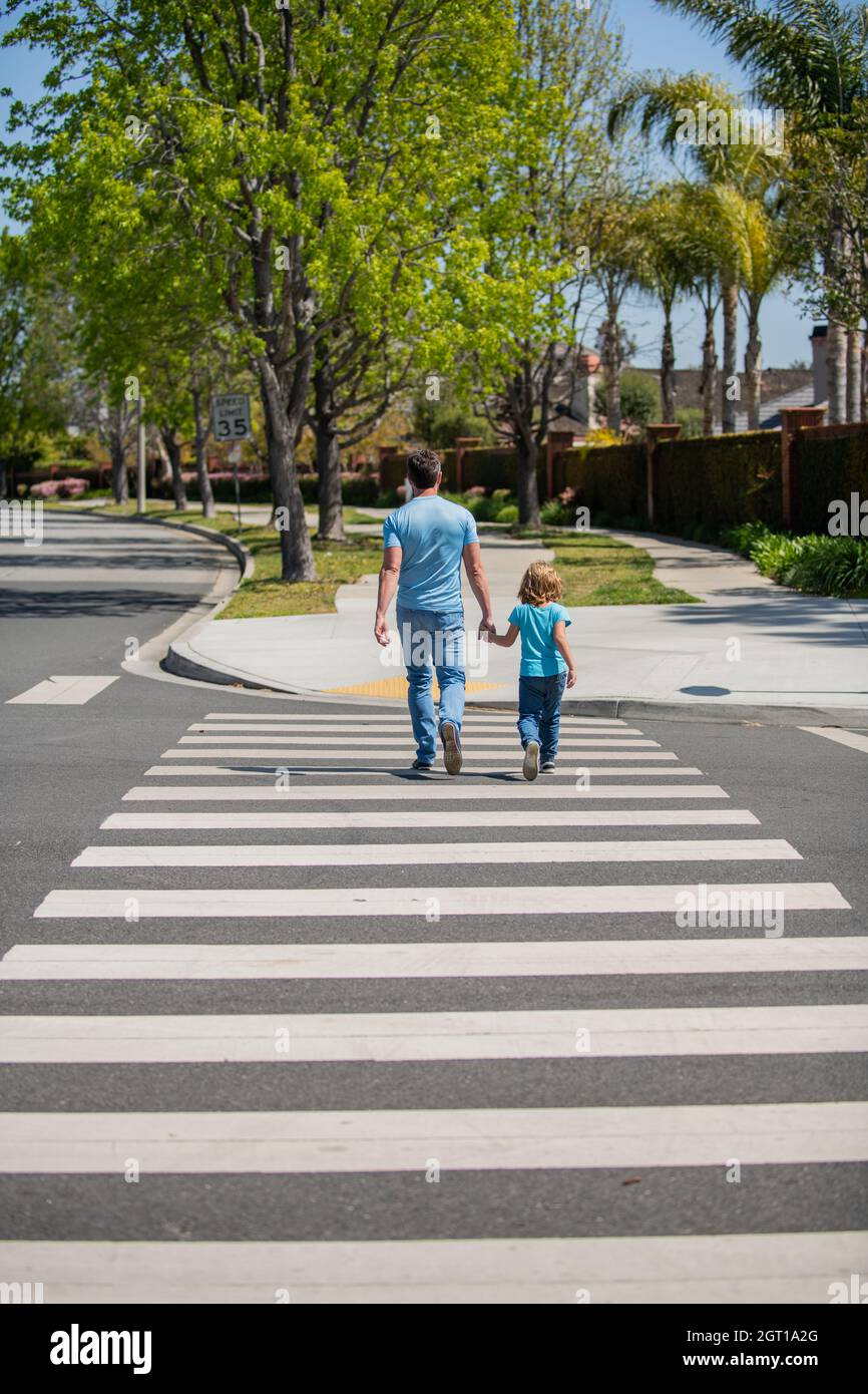 father and son walk on zebra crossing. family value. parent leading ...