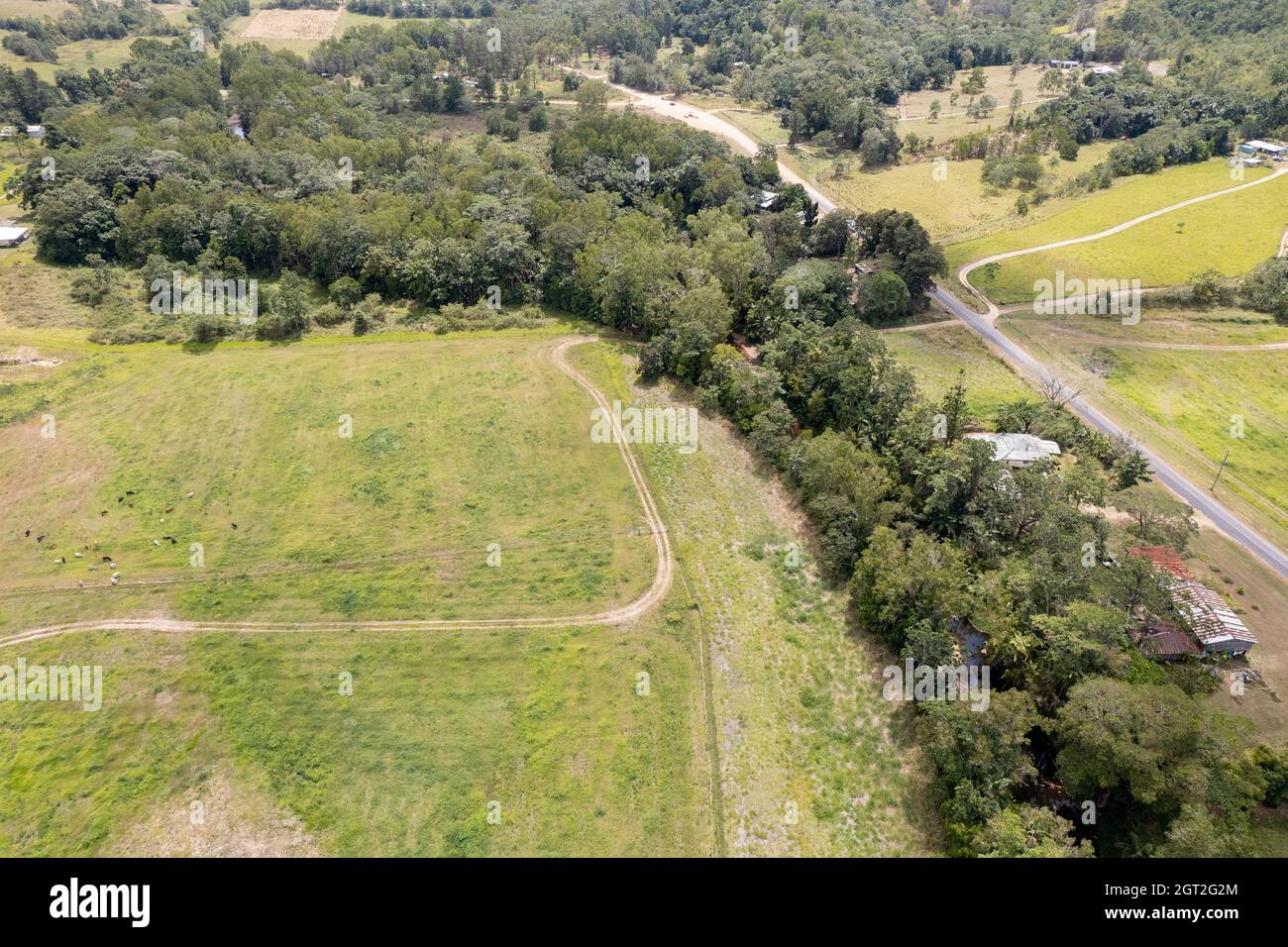 Aerial landscape over fields, bushland, homes and roads leading into a ...