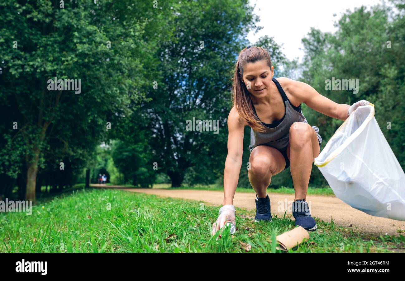 Full Length Of Woman Picking Up Garbage On Grass Against Trees Stock ...
