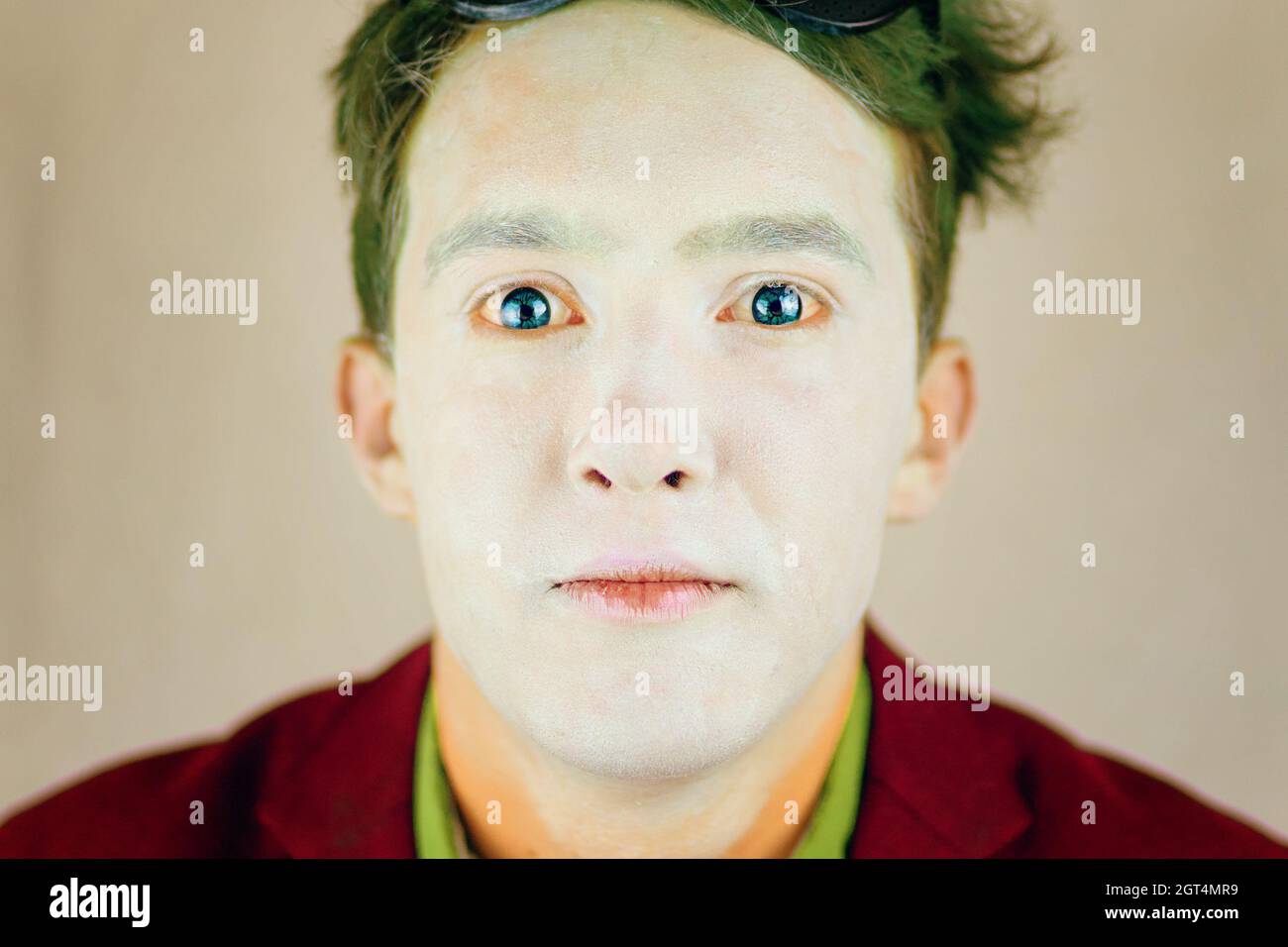 Actor with white makeup on face and green hair. Greasepaint of clown or ...