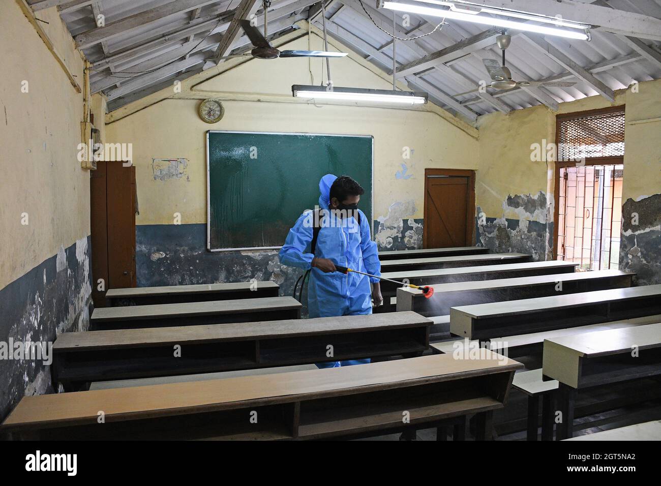 A man wearing a Personal Protective Equipment (PPE) disinfects a ...