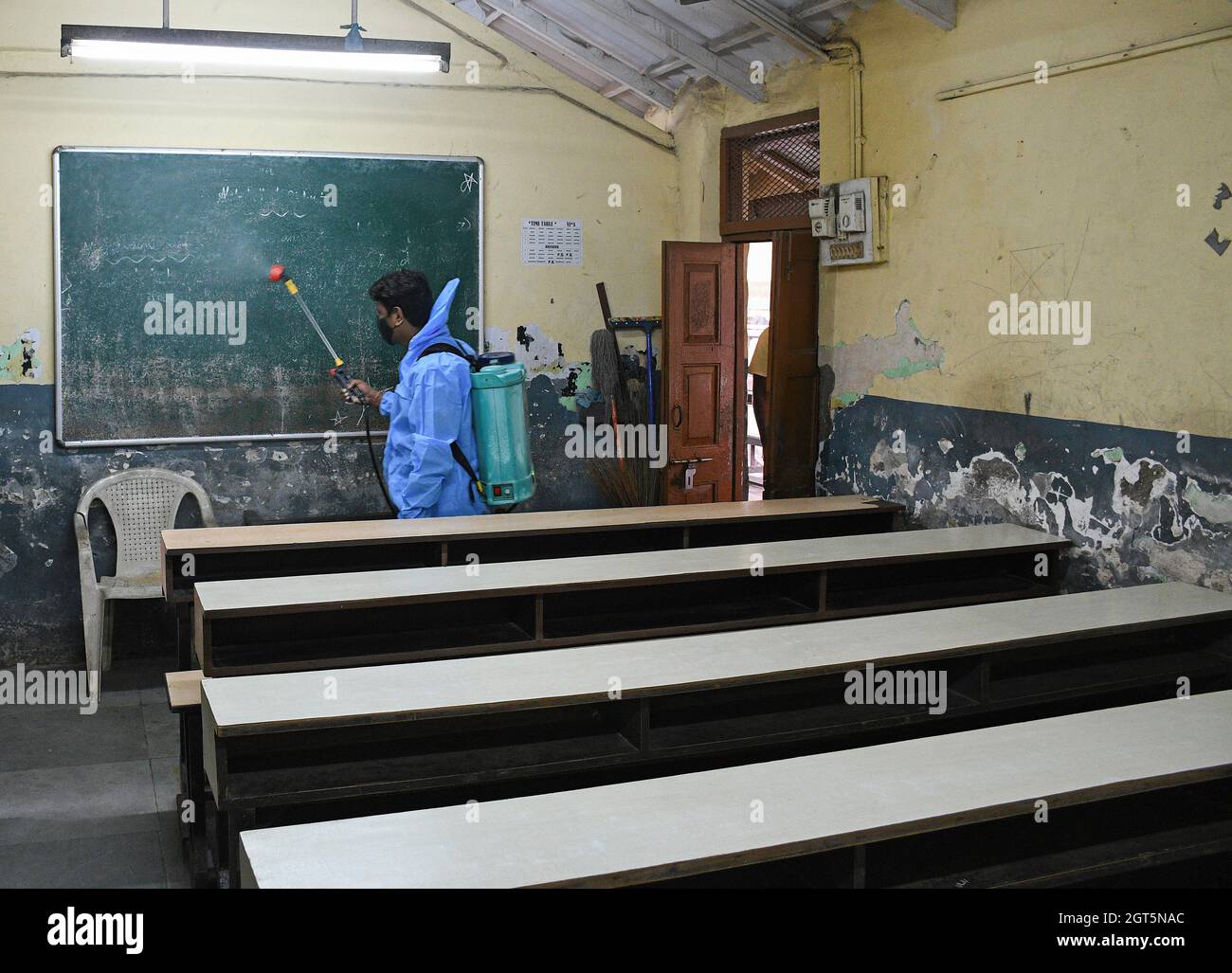 A man wearing a Personal Protective Equipment (PPE) disinfects a ...