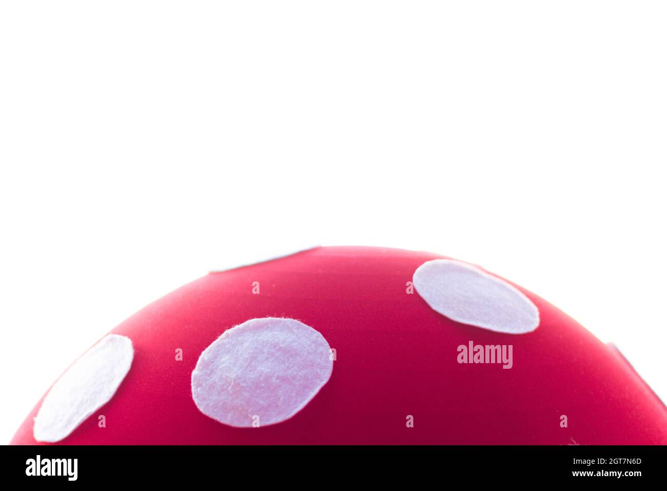 Close-up shot of the top of a red and white toadstool toy on white ...