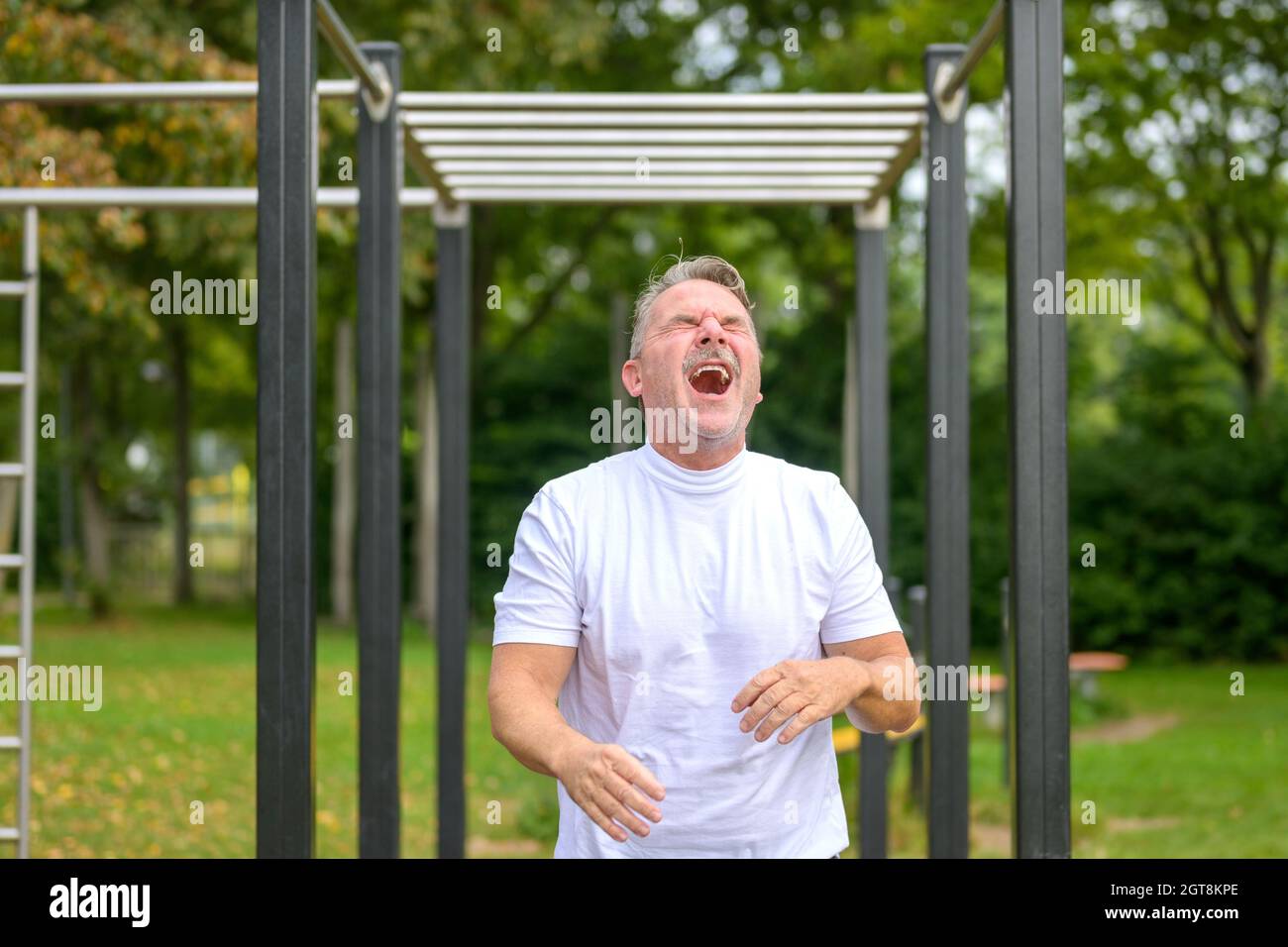 Senior man yelling in pain after injuring himself working out on ...