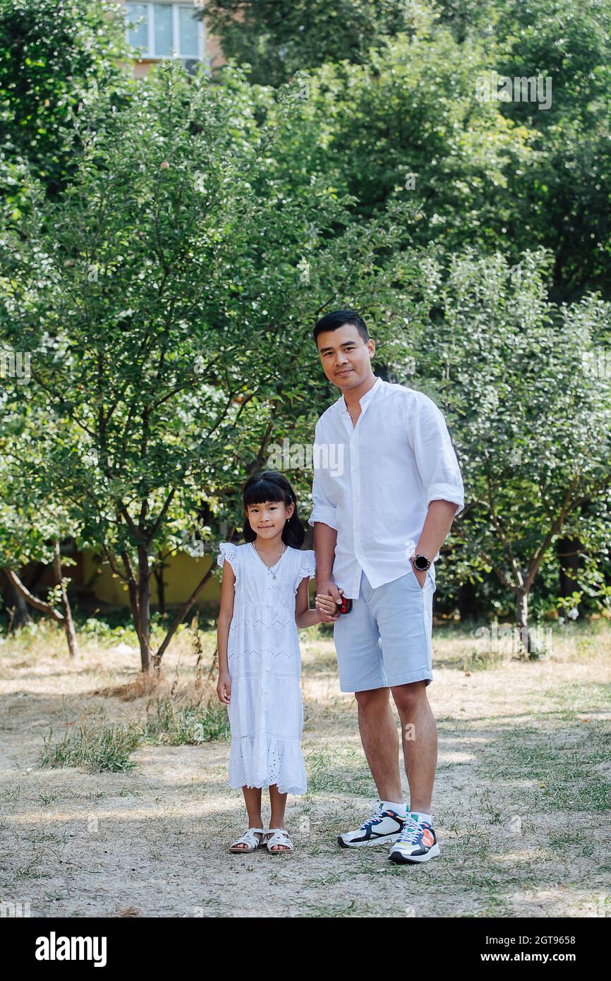 Handsome asian father holding the hand of his daughter standing on a ...