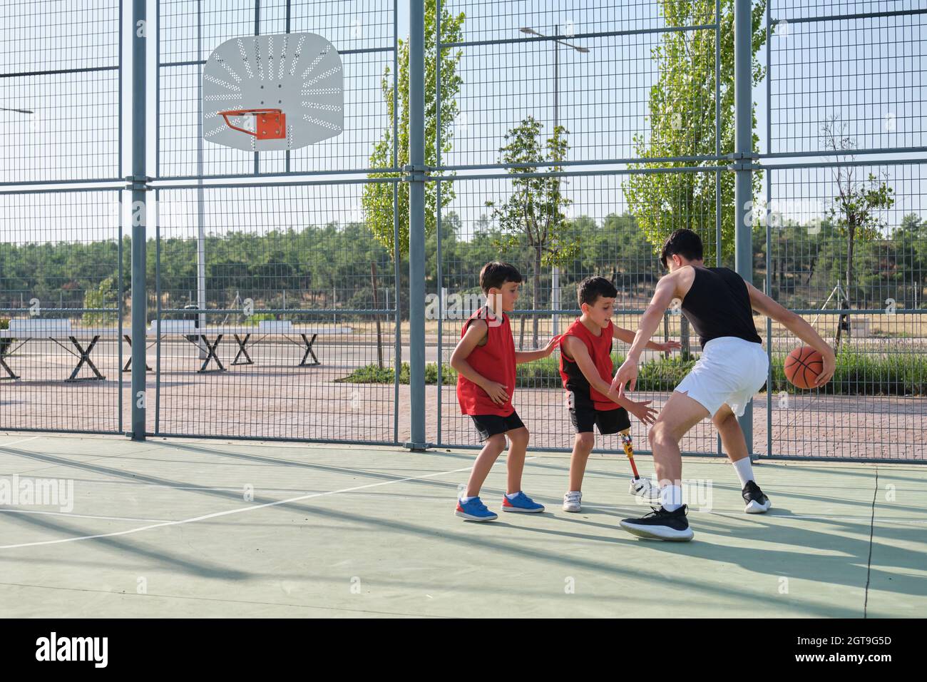 Basketball trainer play basketball with two children, one has a leg ...