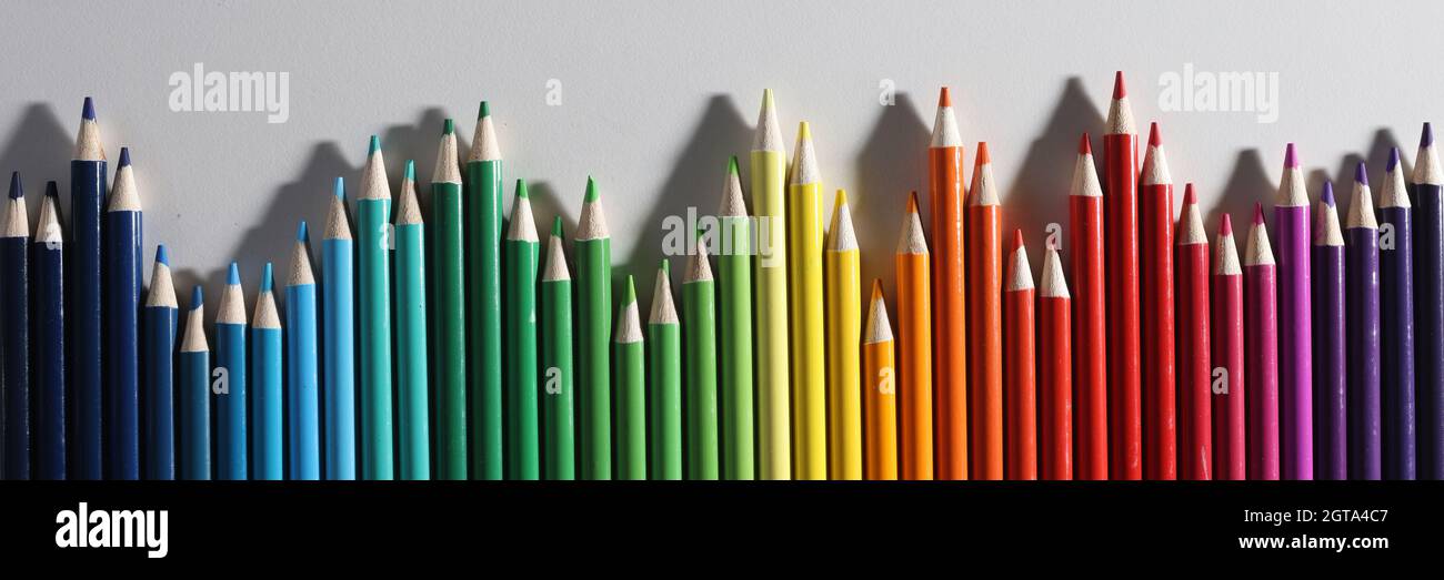 Colored pencils of different shades lie in row on white background ...