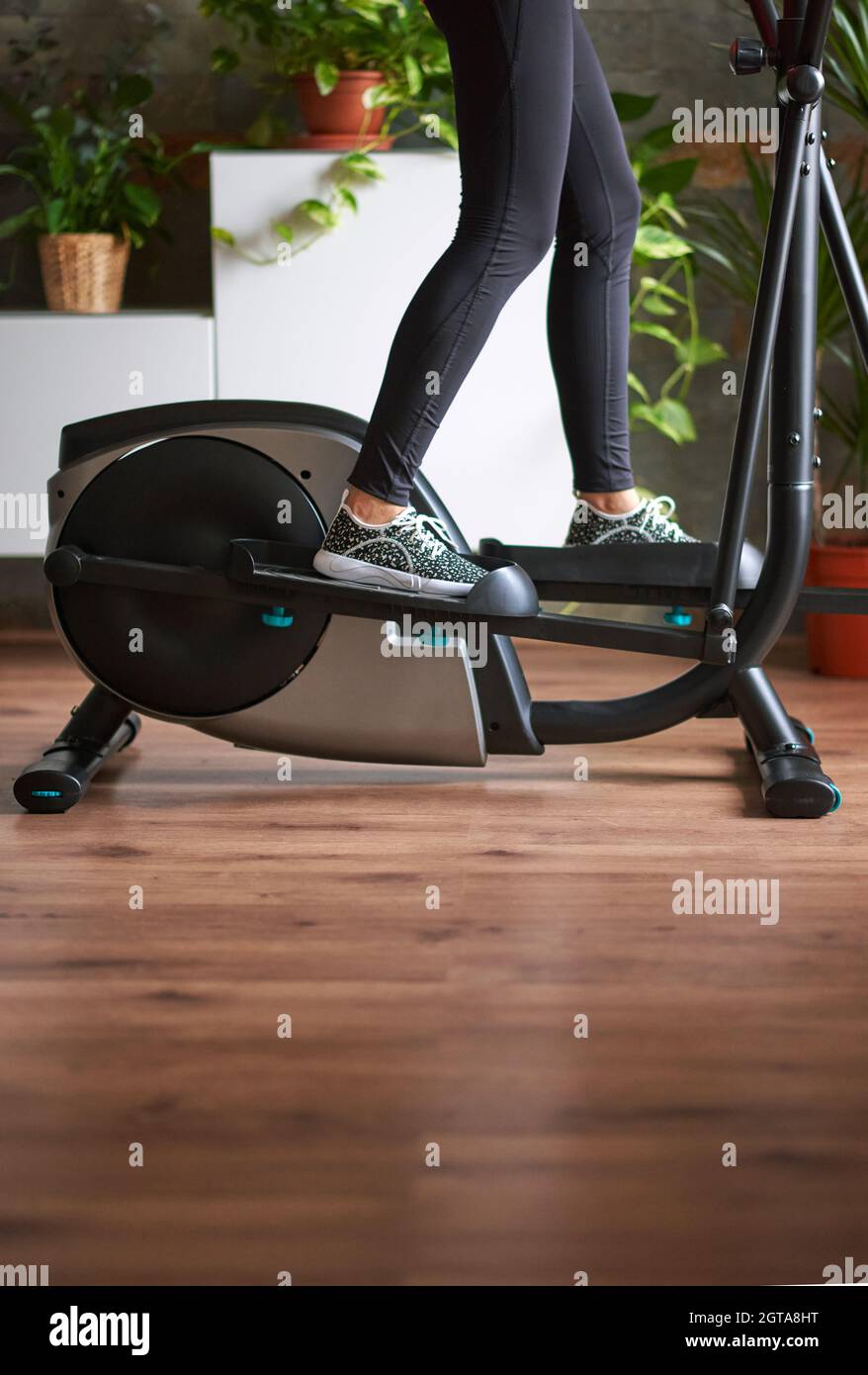 Legs of woman training on elliptical bike in living room at home Stock ...