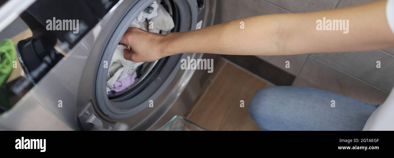 Female hands getting out clean clothes from washing machine in bathroom ...