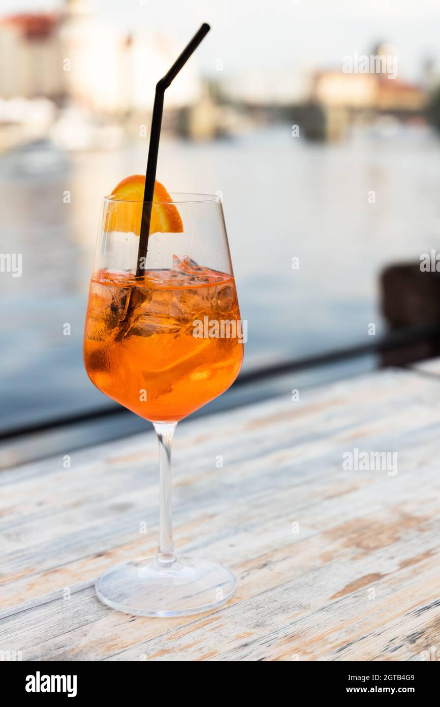 Glass of bright orange cocktail stands on a table of an outdoor bar ...