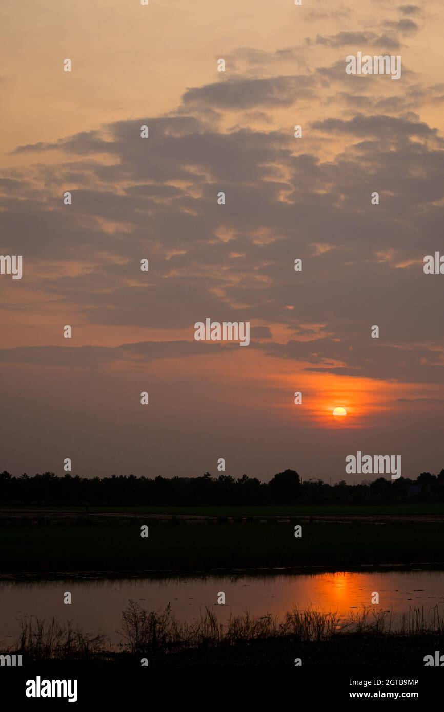 Dramatic sunset landscape with dark sky, silhouettes of trees and lake ...