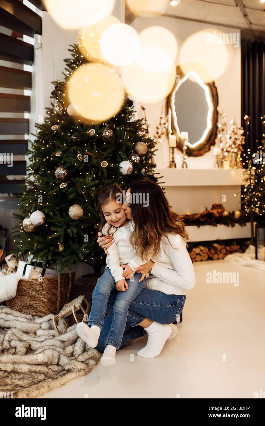 Portrait of beautiful woman kissing at the cheek little daughter ...