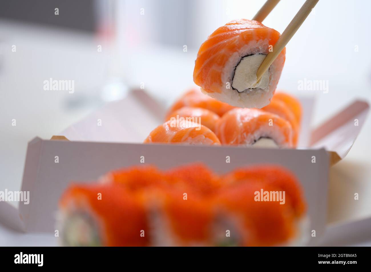 Hand with disposable chopsticks holds sake nigiri sushi with salmon fish Stock Photo - Alamy