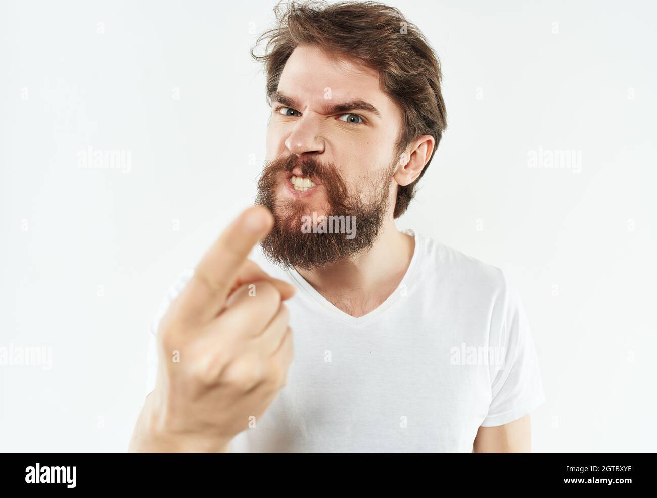 Man in a white t-shirt irritated facial expression light background ...