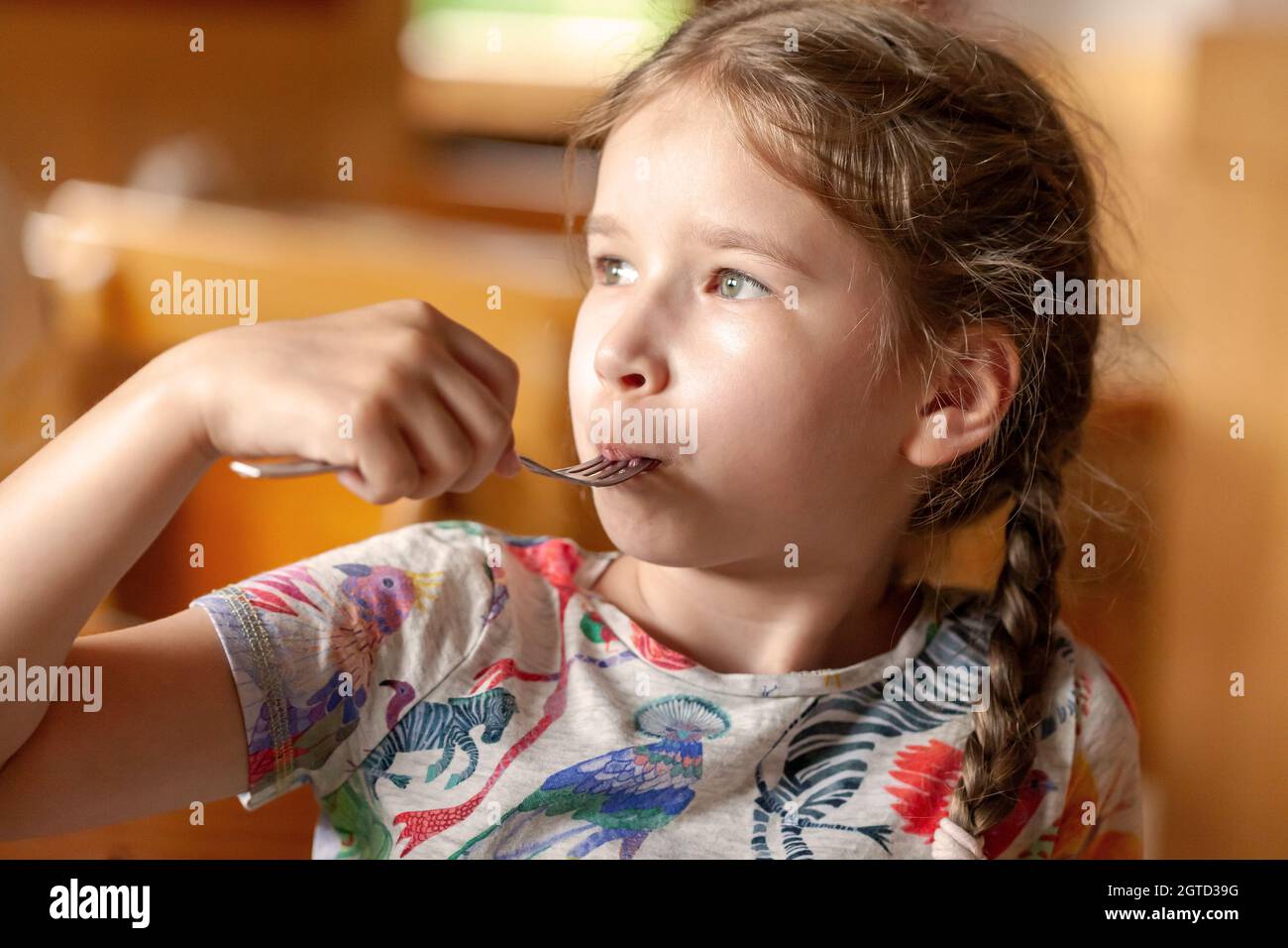 Young school age girl, little child eating her meal, holding a fork in ...