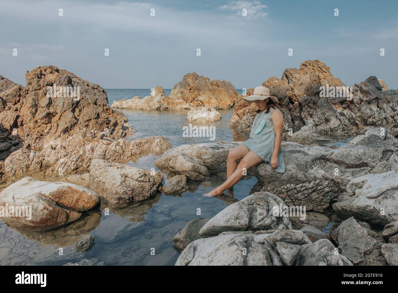Beautiful Woman Sitting On Rock Over Sea Stock Photo - Alamy