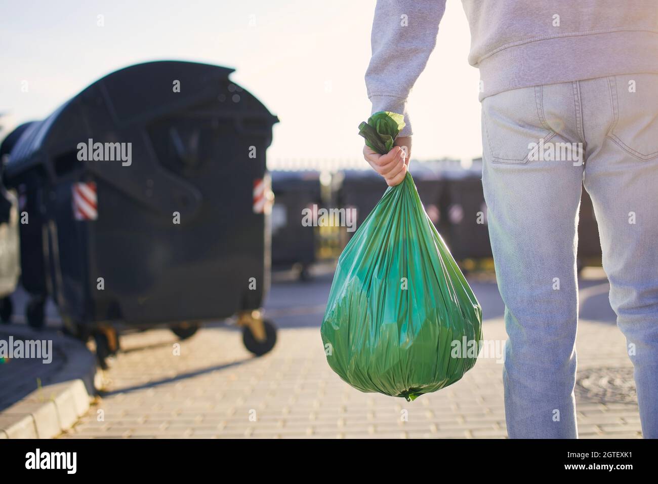 Man walking with rubbish. Rear view of person carrying plastic bag ...