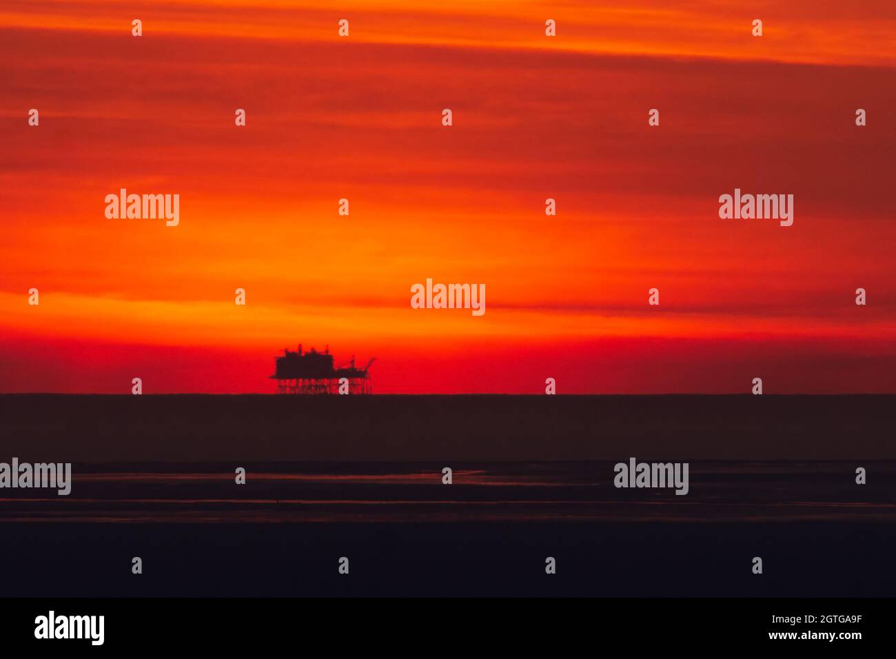 Silhouette of an oil rig or platform on a distant horizon against ...