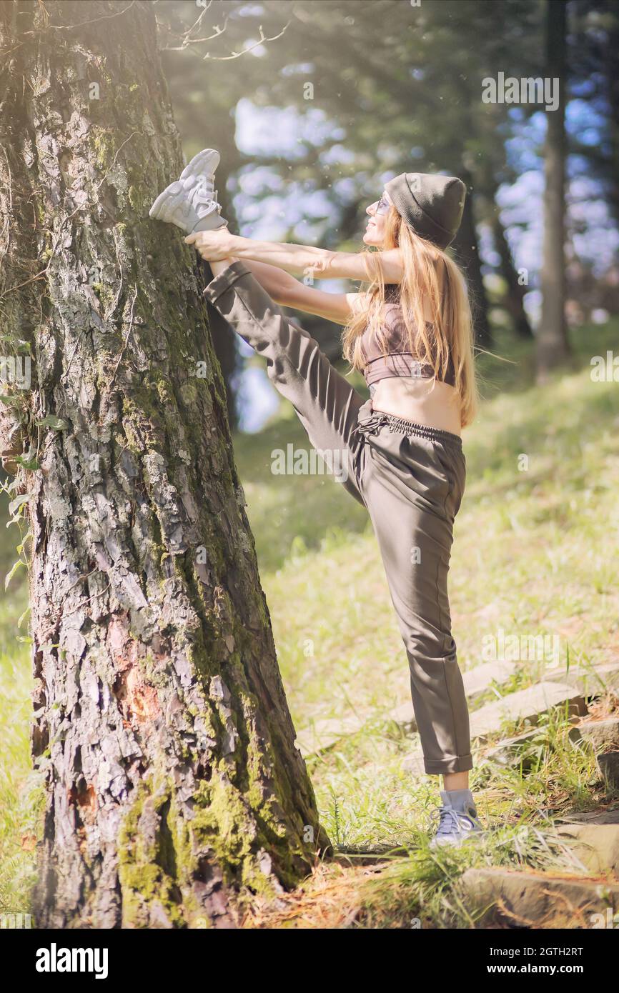 A woman in a sports outfit does a stretch by throwing her foot on the ...