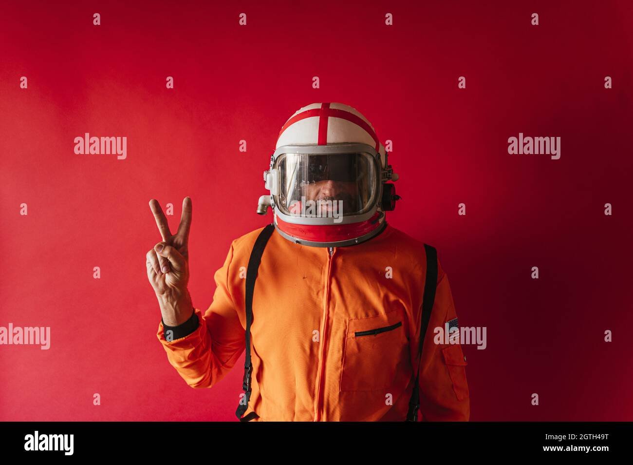 Astronaut with a helmet and an orange space suit showing the peace sign ...
