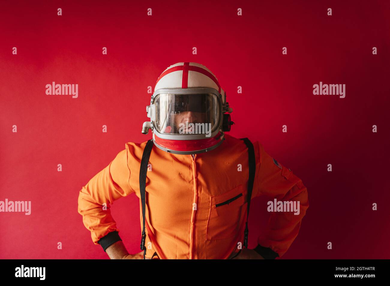 Astronaut with a helmet and an orange space suit on a red background ...