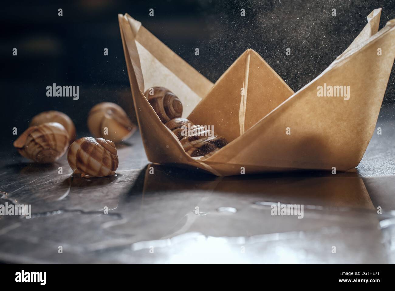 Snails in paper boat on metal restaurant kitchen table Stock Photo - Alamy