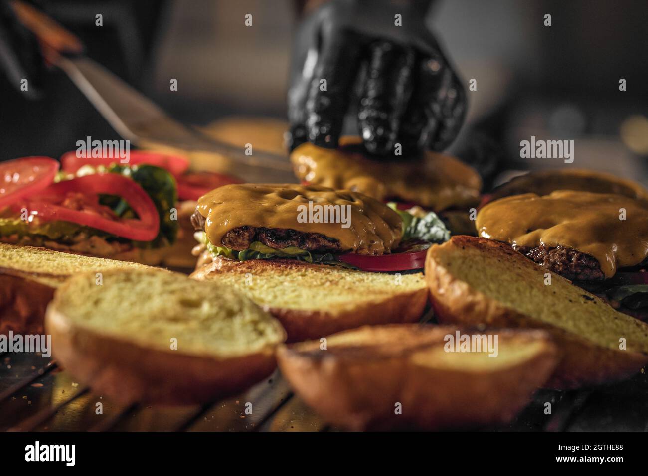 Process of cooking cheeseburgers on the grill. Chef in black gloves ...