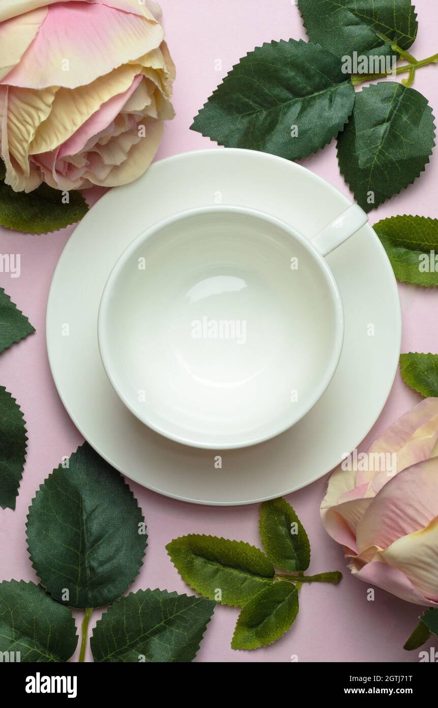 Top view of an empty teacup with pink roses and leaves on a pink ...