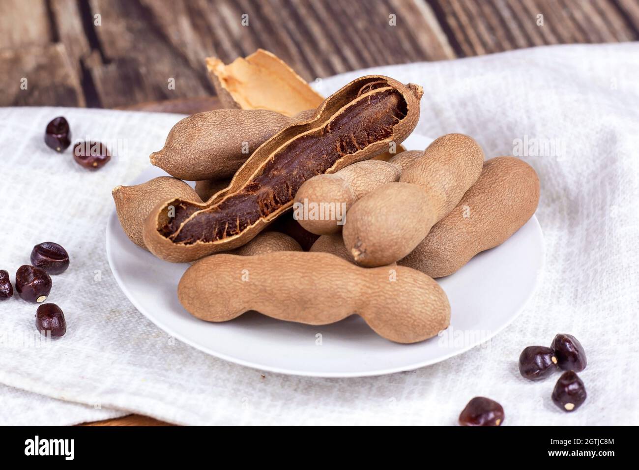 Fresh brown tamarind fruit pods ripe with seeds on light textile ...