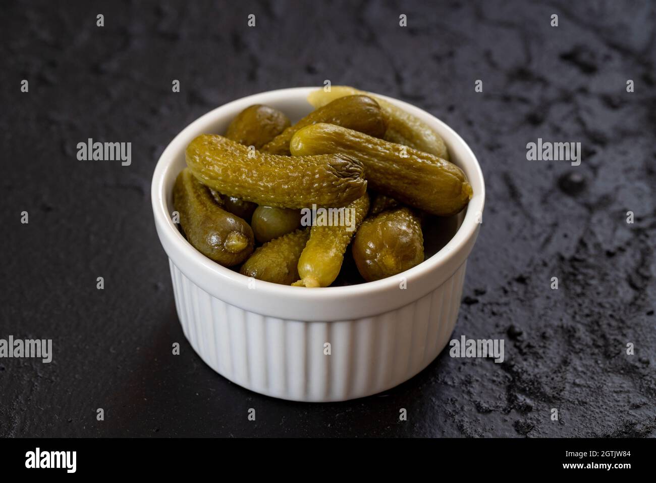 Crunchy pickled cornichons in a white ceramic bowl. Marinated green ...