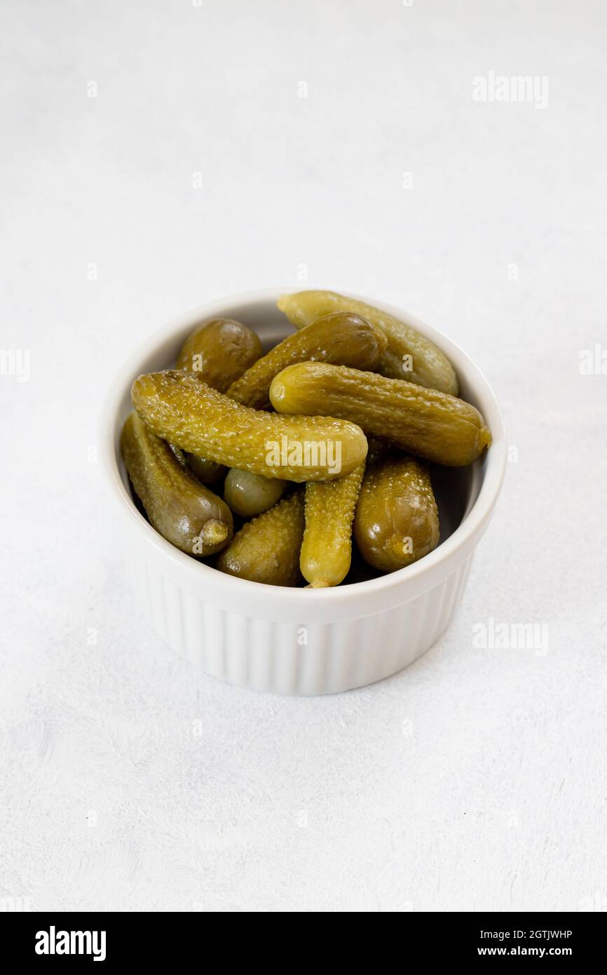 Crunchy pickled cornichons in a white ceramic bowl. Marinated green ...