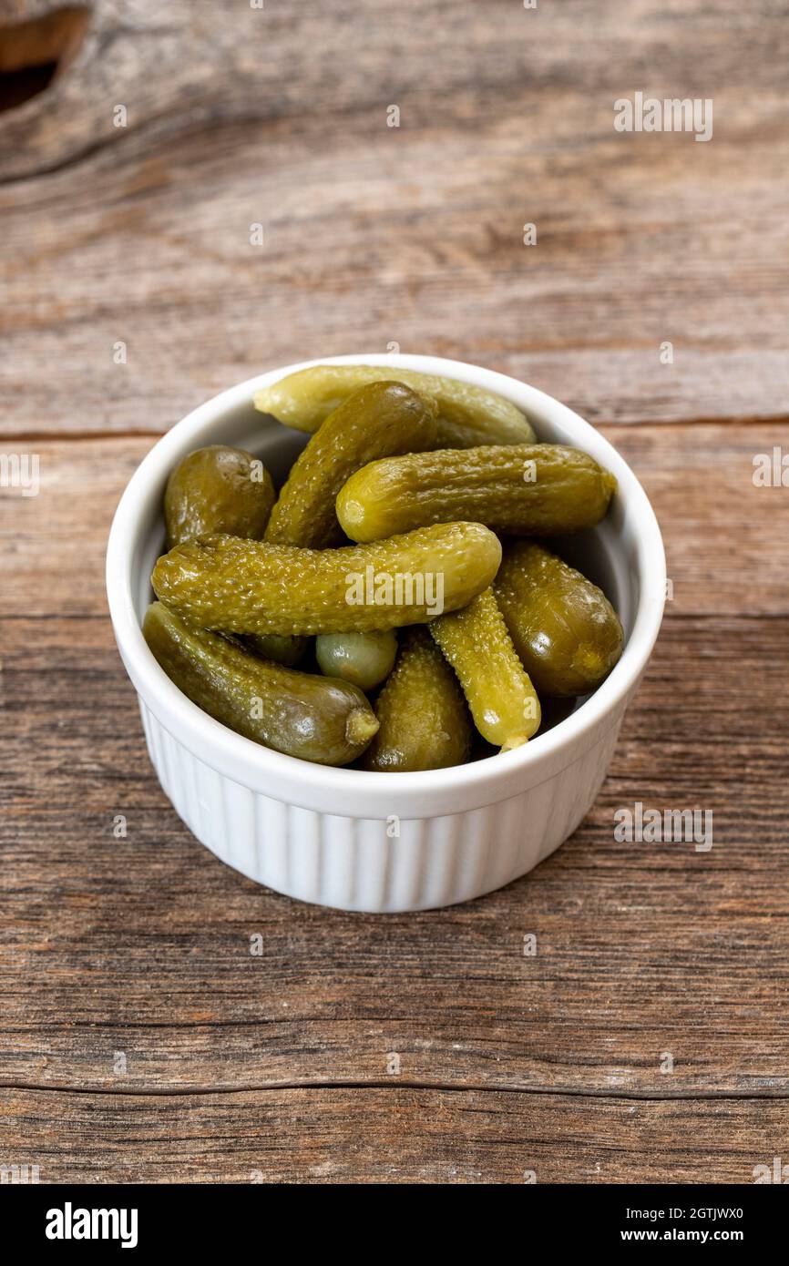Crunchy pickled cornichons in a white ceramic bowl. Marinated green ...