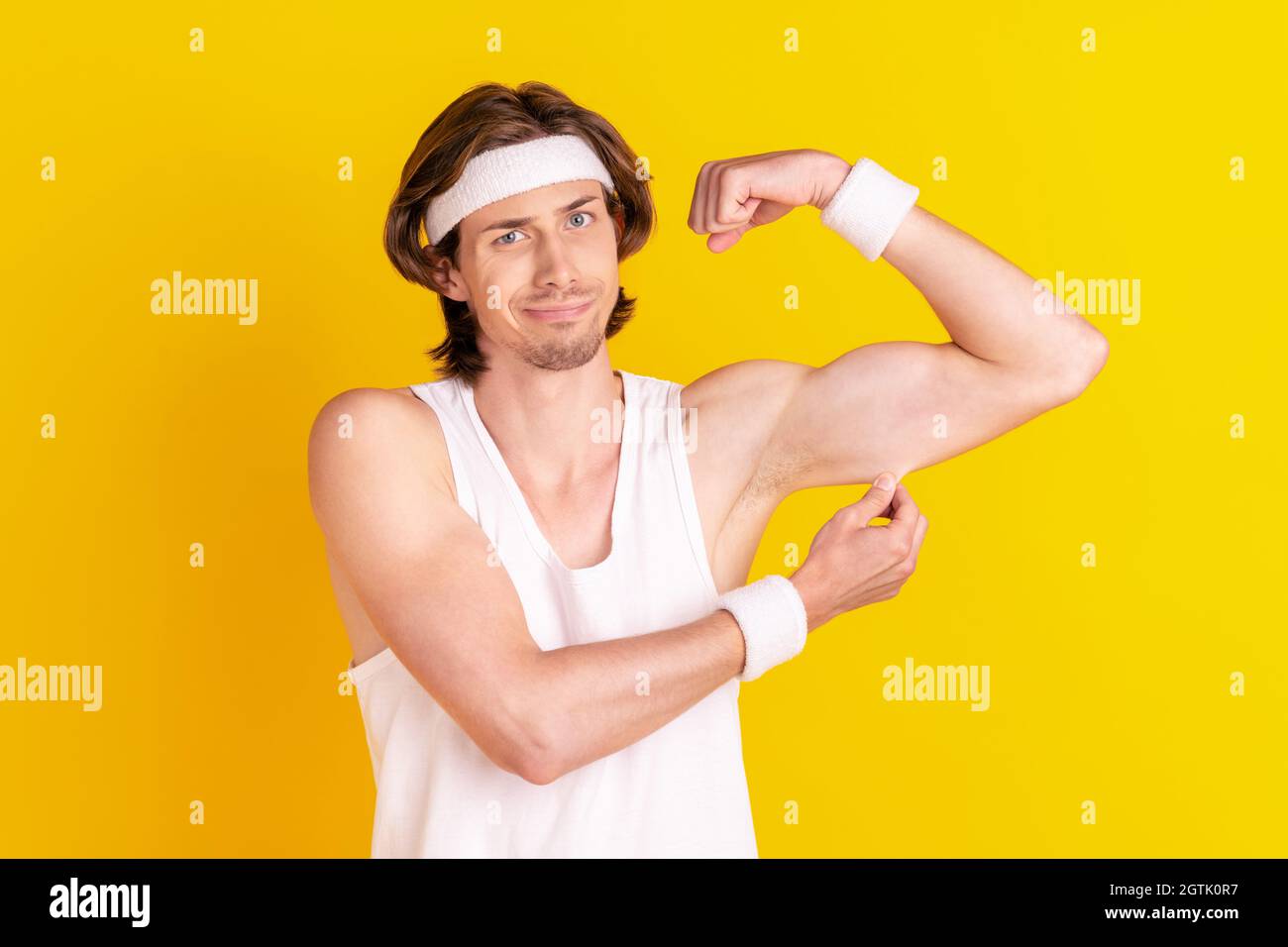 Portrait of attractive puzzled sportive guy pulling weak muscles skin ...
