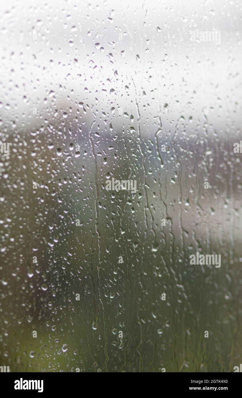 Rainy day through the window on cloudy grey sky and city buildings ...