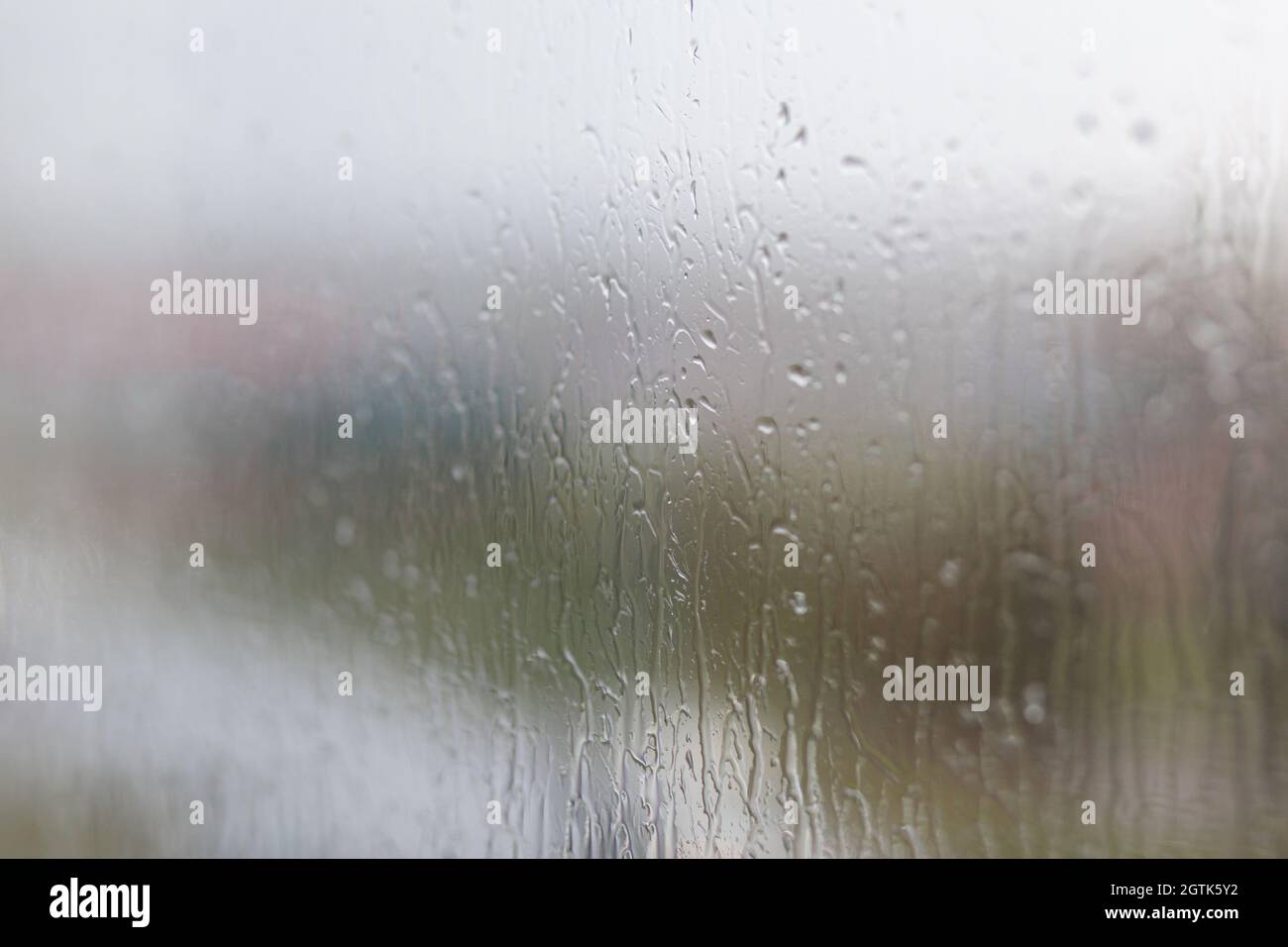 Rainy day through the window on cloudy grey sky and city buildings ...