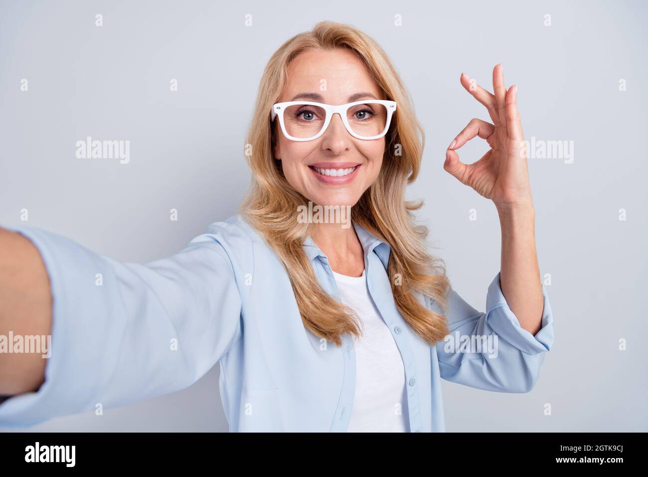 Portrait of young pretty smiling female in spectacles take selfie ...
