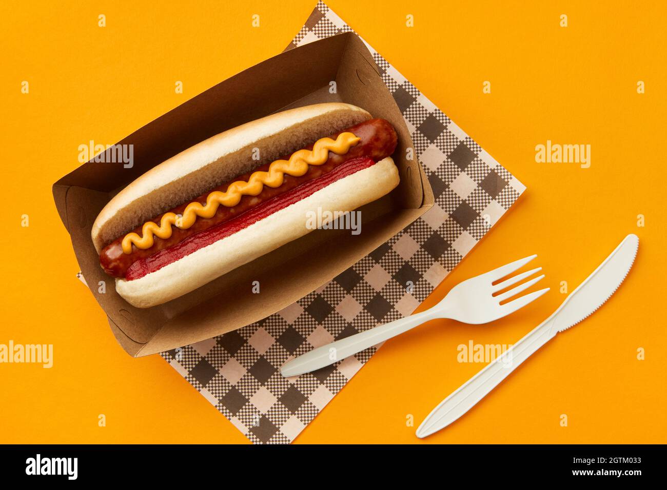 Classic hot dog with wurst, ketchup and mustard on orange background ...