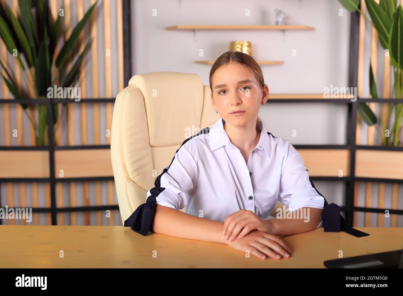 Young beautiful girl in office style looks at the camera. A teenager in ...