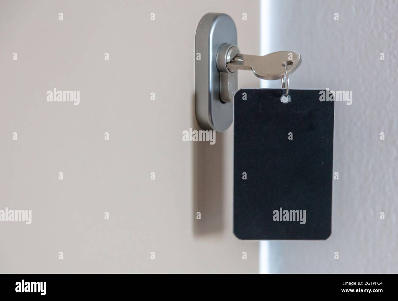 Door key with blank label in the keyhole. Steel key ring, room key and ...