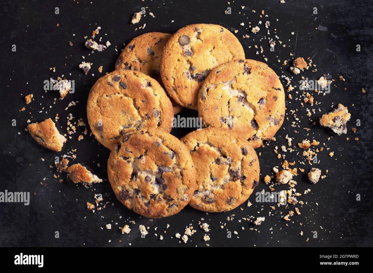 Pile of chocolate chip cookies and crumbs on an old black metal ...