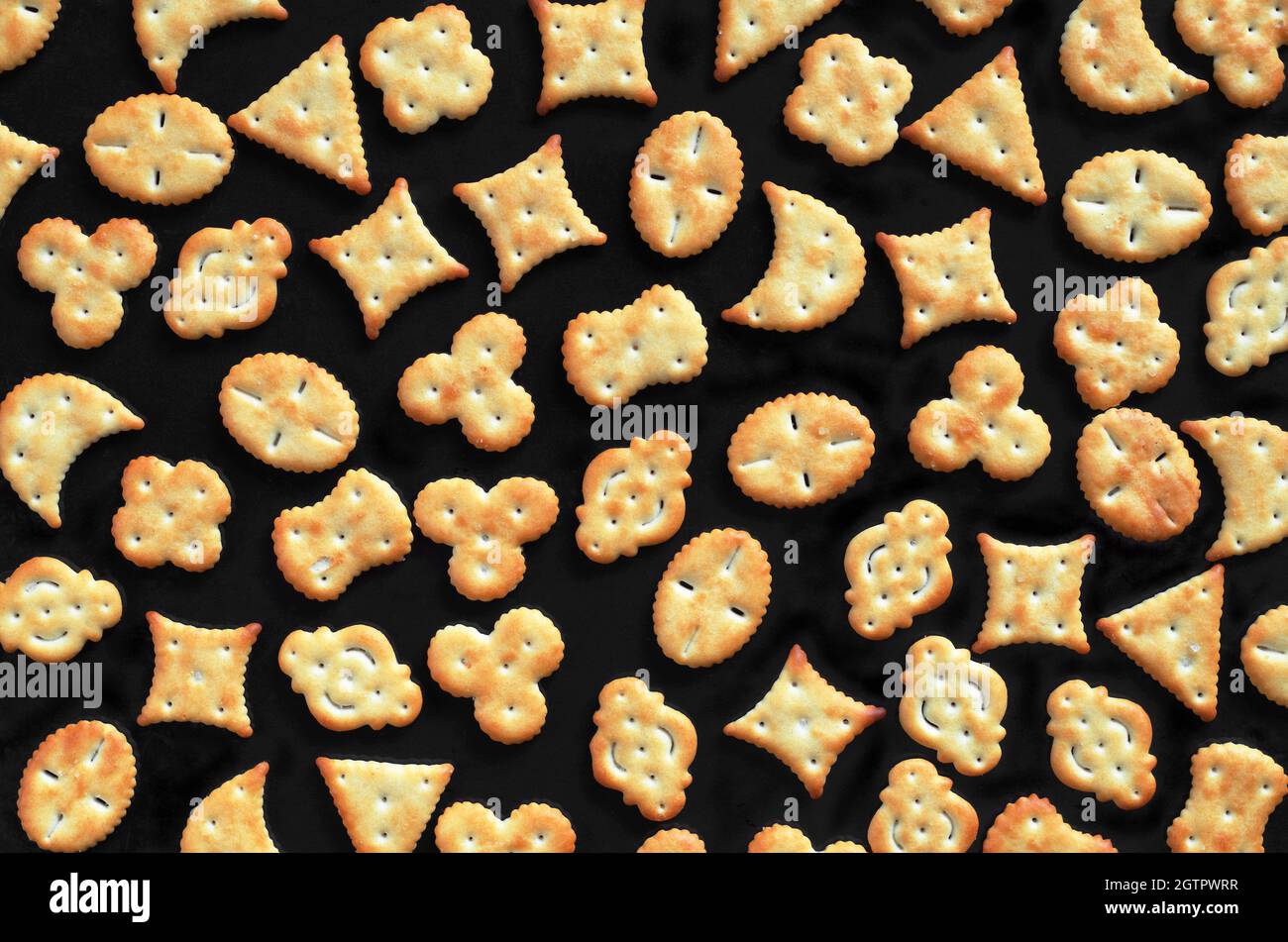 Background with various small salty crackers on black metal Stock Photo ...