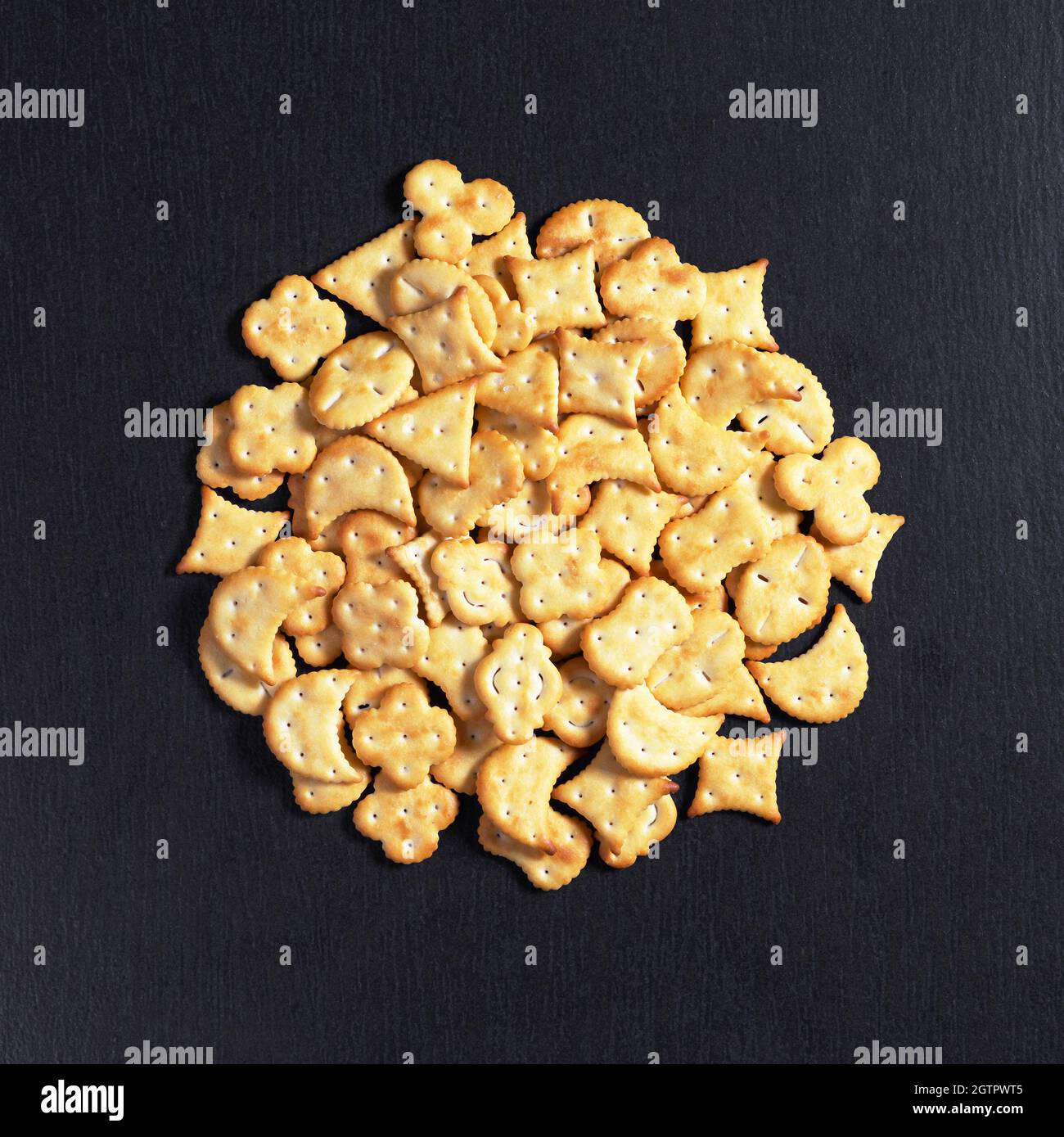 Heap of small crackers of different shapes on black stone background ...