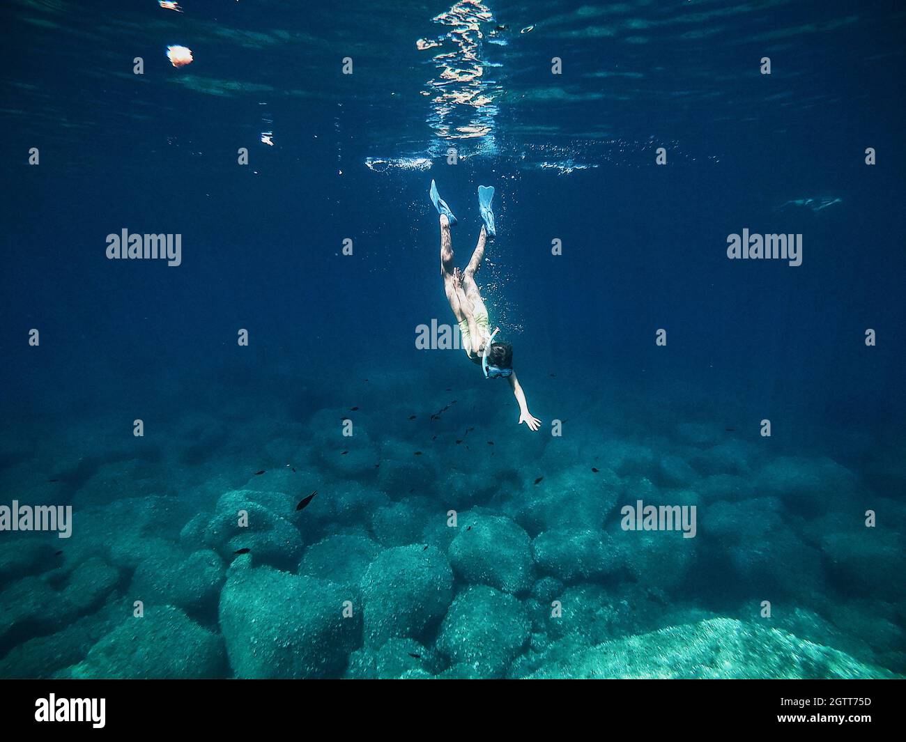 Adult person diving in the sea under the sunlight through the water ...