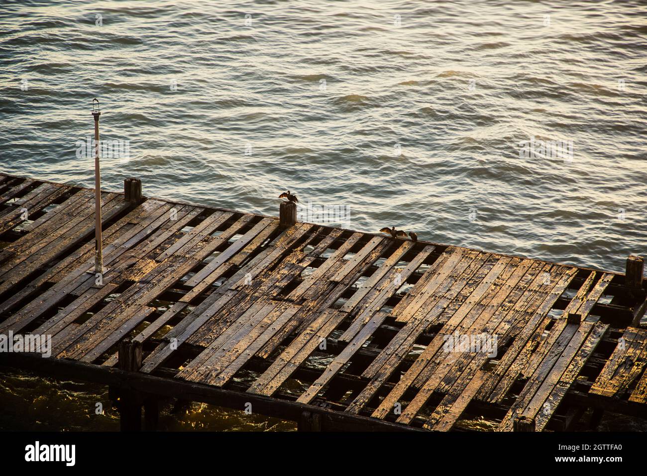 Old and abandoned wooden pier with the afternoon sun shining on it ...