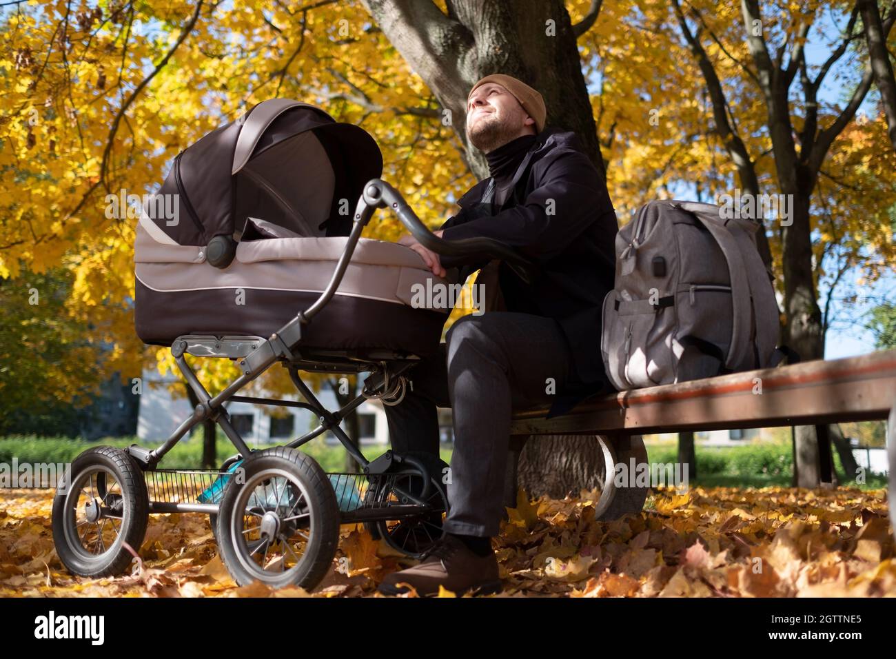 Happy young father with pram sitting on bench in nature at park Stock ...