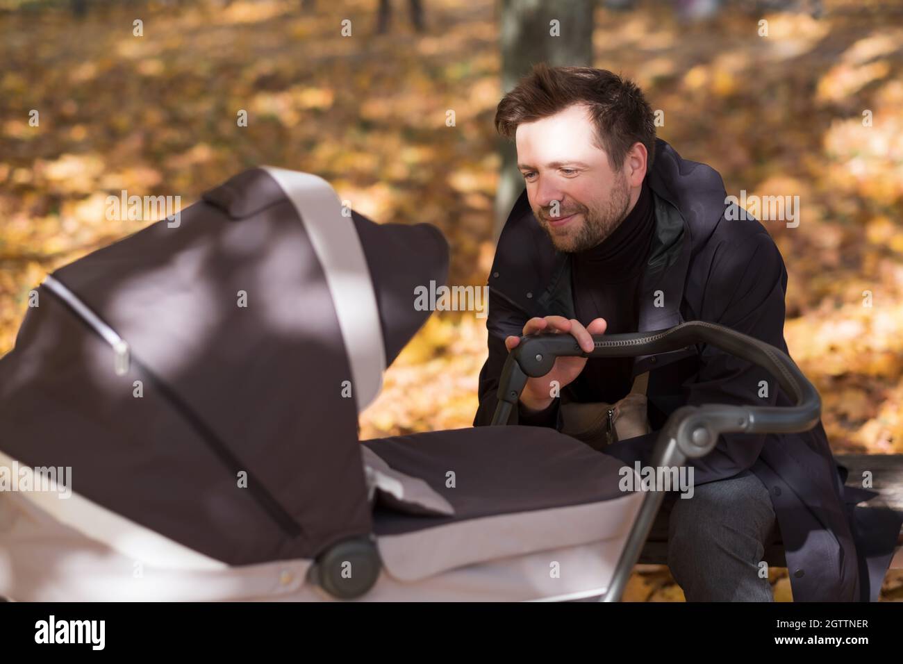 Happy young father with pram sitting on bench in nature at park Stock ...